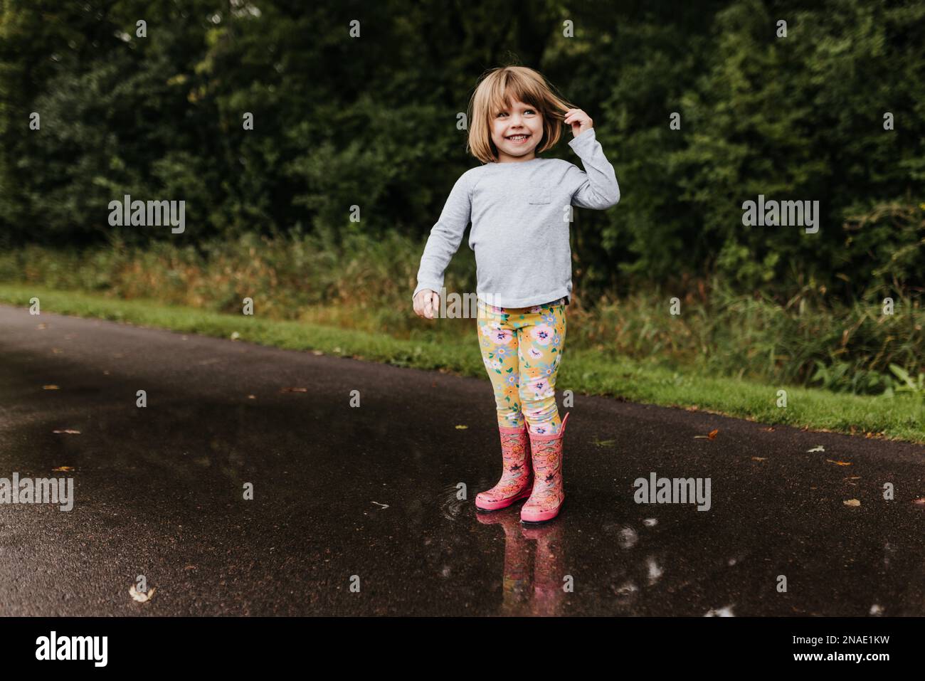 Young girl stands in puddle outside on walking path during Fall Stock ...