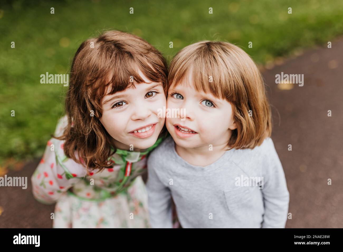 Close up of sisters squishing cheeks while standing outside Stock Photo ...