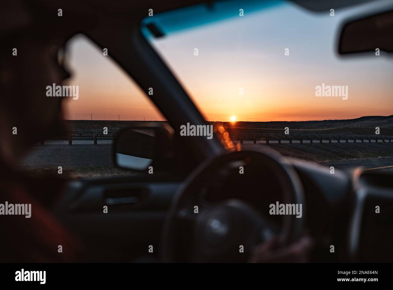 Sunrise through windshield of a car with a man driving Stock Photo - Alamy