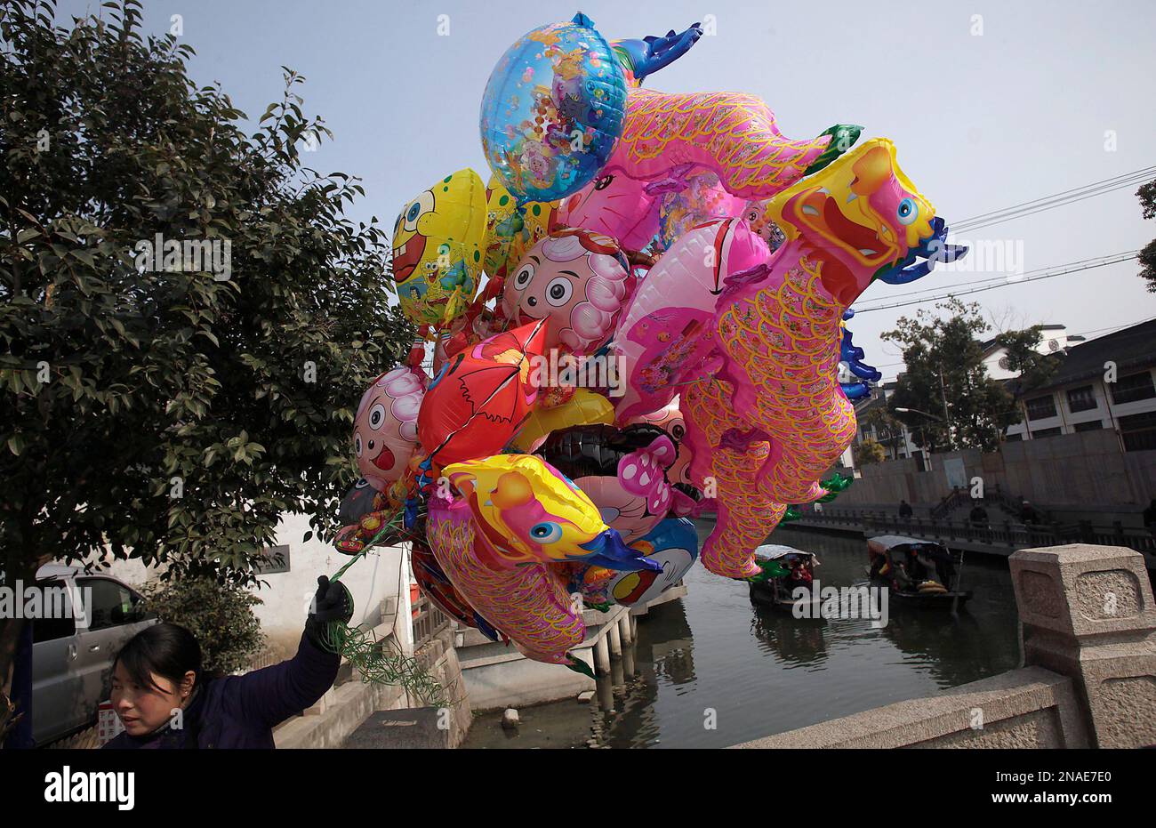 A woman sells balloons including dragon-shaped ones to tourists in ...