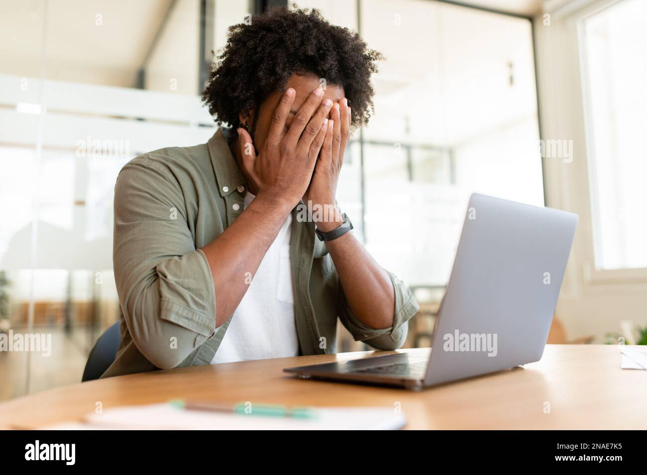 Tired young african-american male employee suffering from severe ...