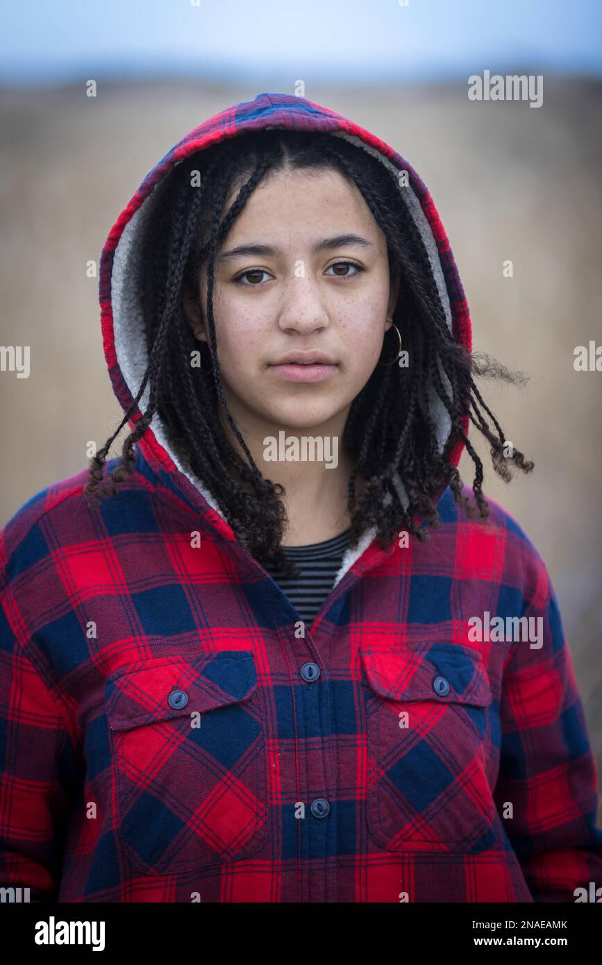 portrait of biracial young woman with serious expression wearing hood ...