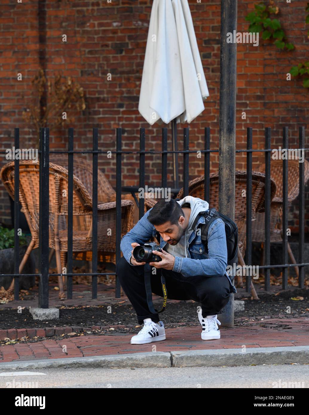 A touristic man shooting with a camera through the street with brick ...