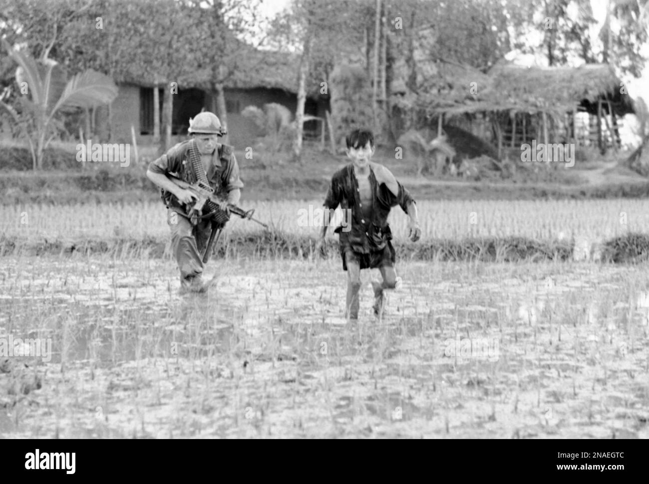 Muddied bedraggled Viet Cong guerrilla suspect is followed by heavily ...