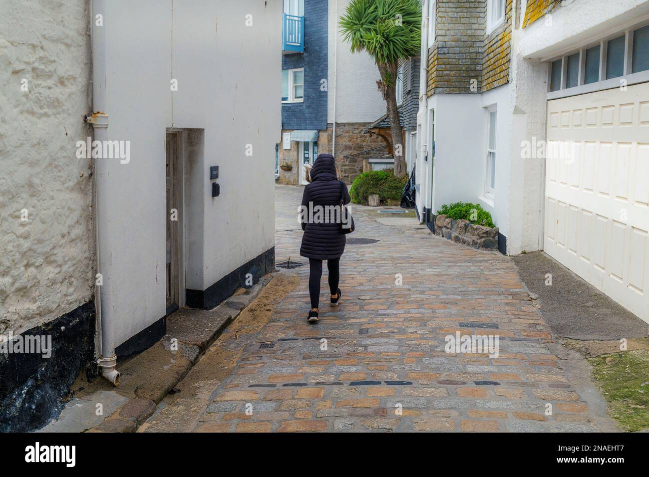 UK weather. A woman walking alone along a cobbled street on chilly day ...