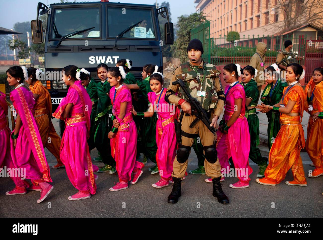 A member of the Delhi Police Swat team stands guard as girls dressed in ...