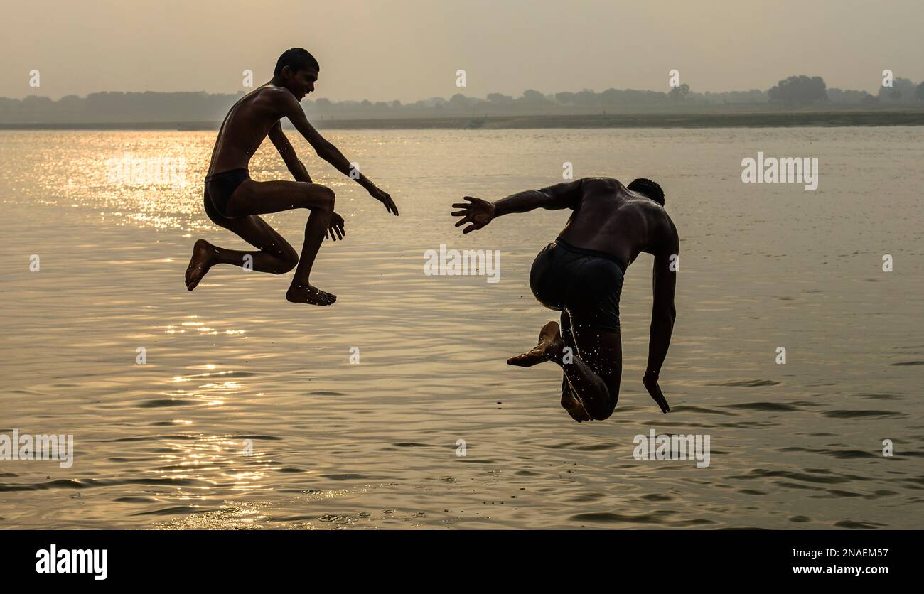 Two boys jumping into the Ganges at sunrise; Varanasi, India Stock ...