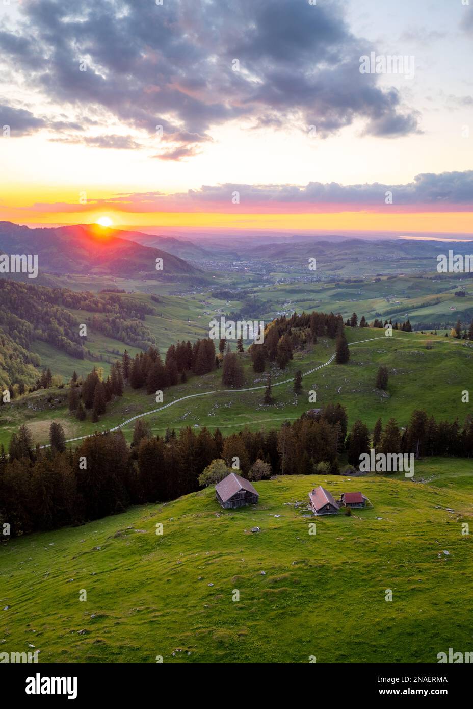 a farm high on the hills during a sunset in the distance you can see a ...