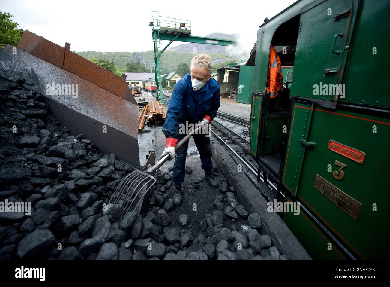 Man shoveling coal in a locomotive on Mt. Snowdon in Wales, England ...