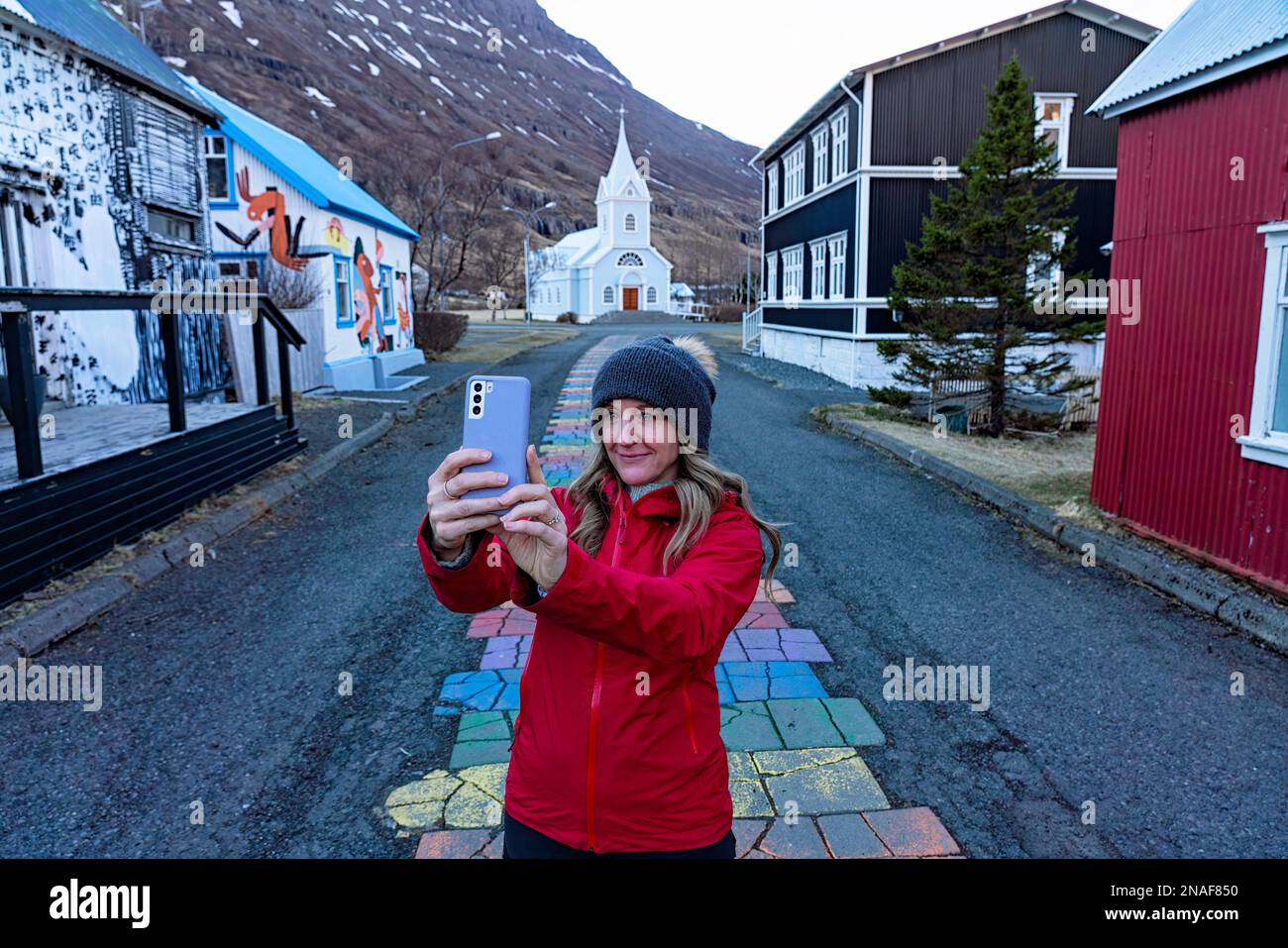 Woman taking a selfie in front of the rainbow walkway and church in ...