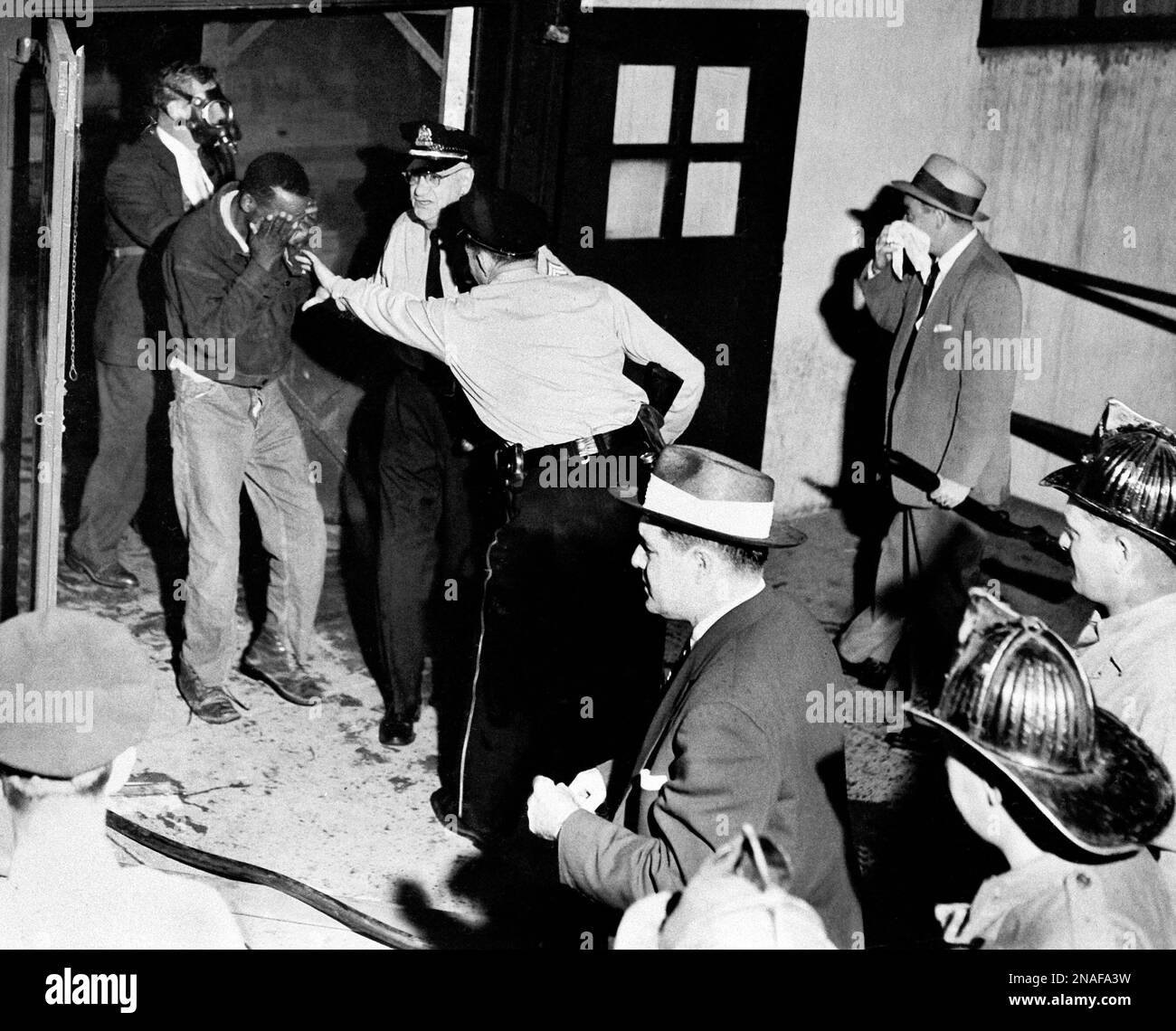 An unidentified prisoner, suffering from tear gas, is led from a cell ...