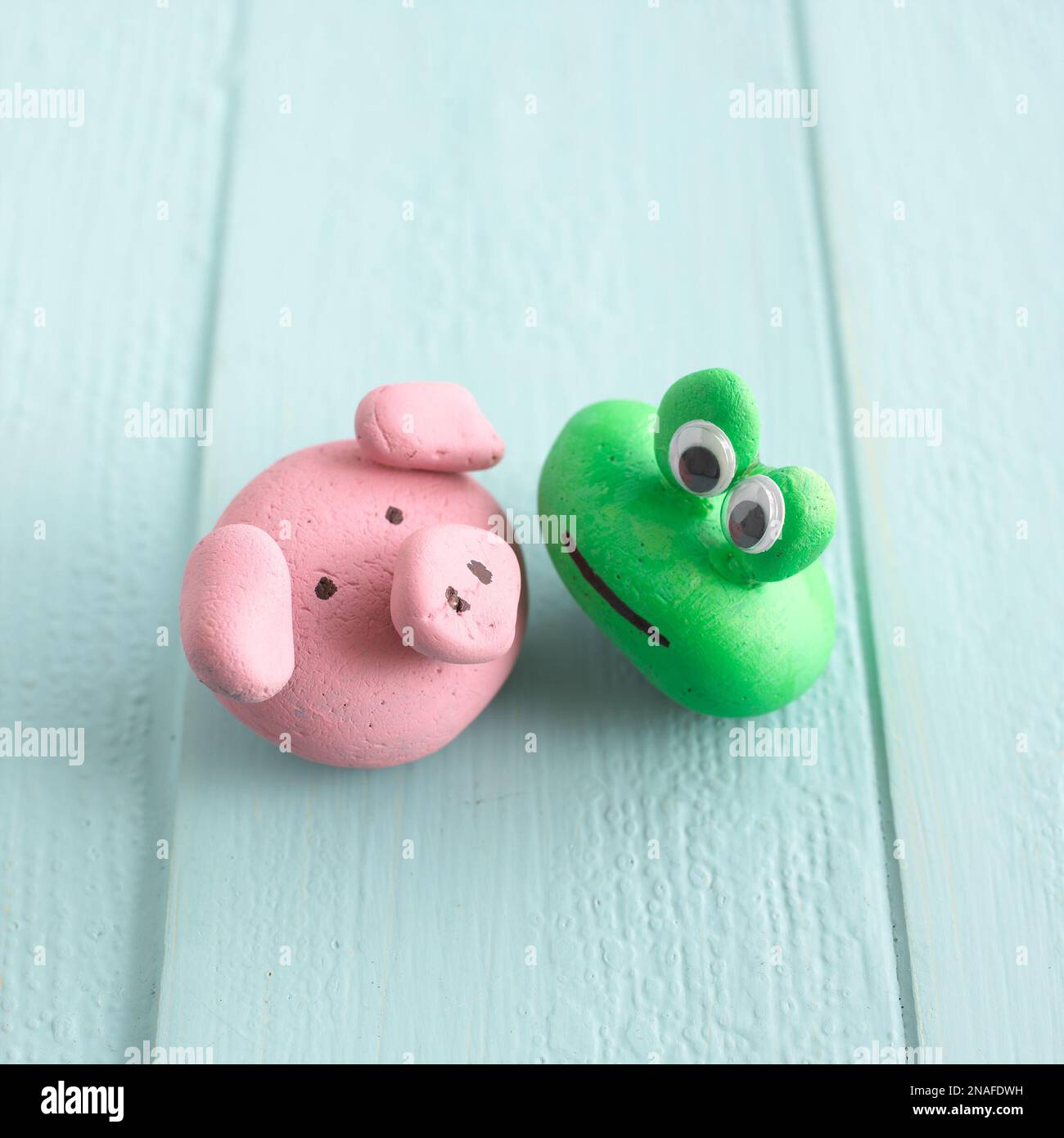 Toy pig and frog made out of painted pebbles Stock Photo - Alamy