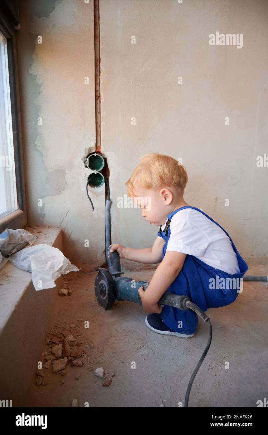 Little boy construction worker holding electric power grinding machine ...