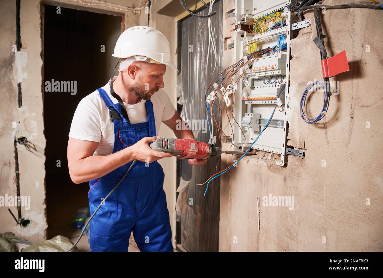 Male builder installing electrical switch panel in apartment. Man in ...