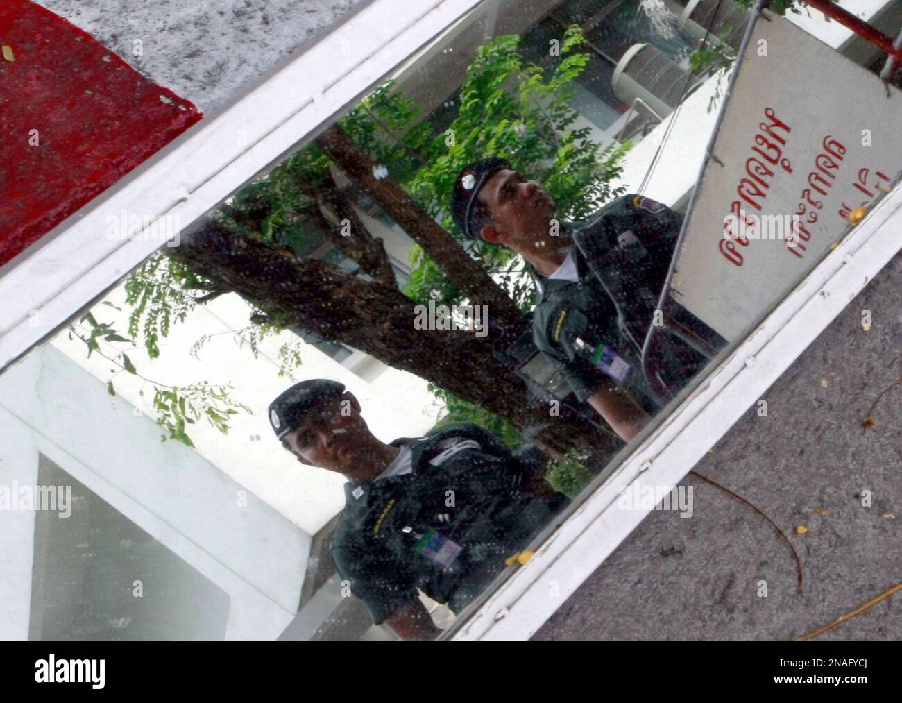 Thai border police officers are reflected on a mirror to check for ...