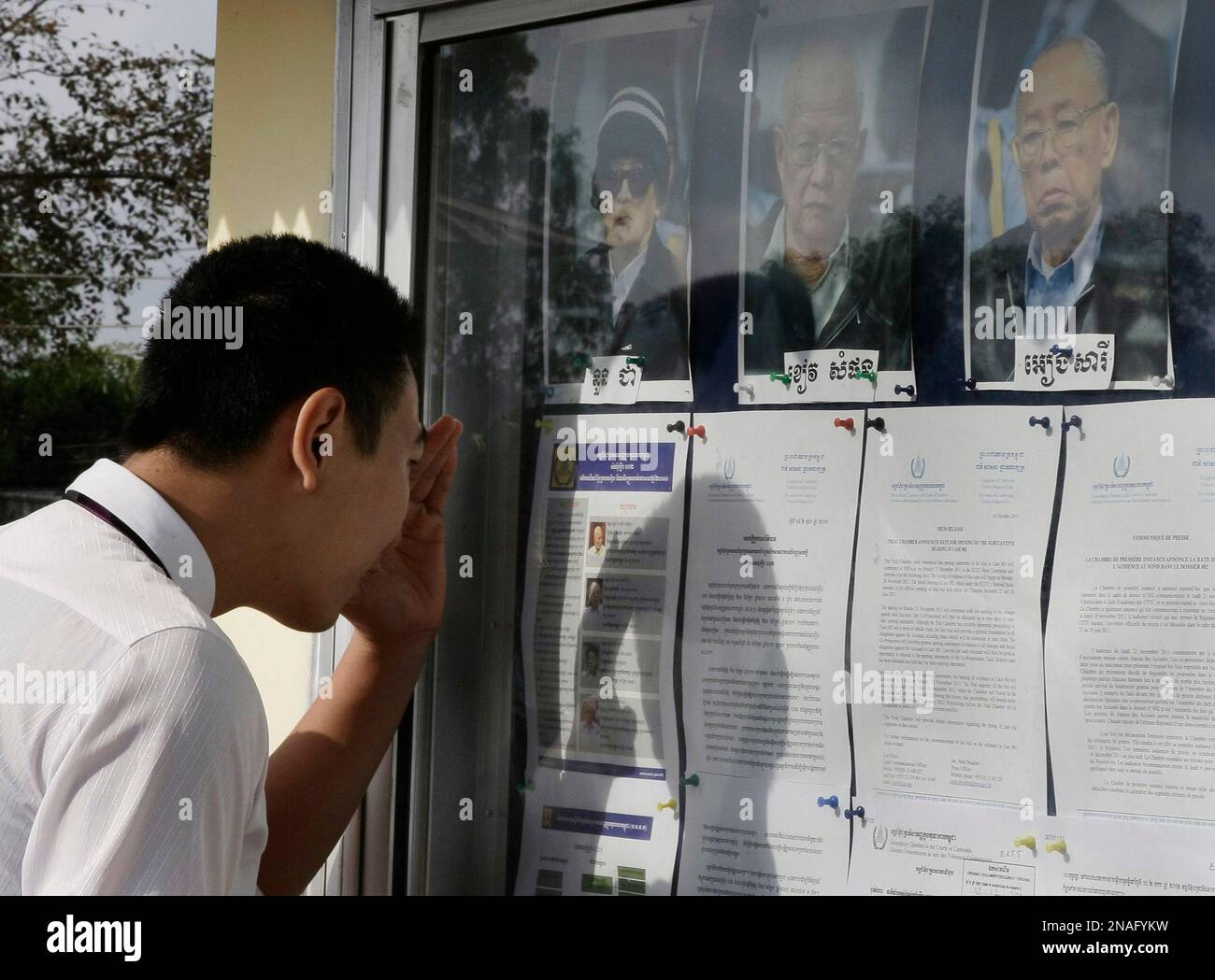 A Cambodian student reads court documents displaying portraits of Khmer ...