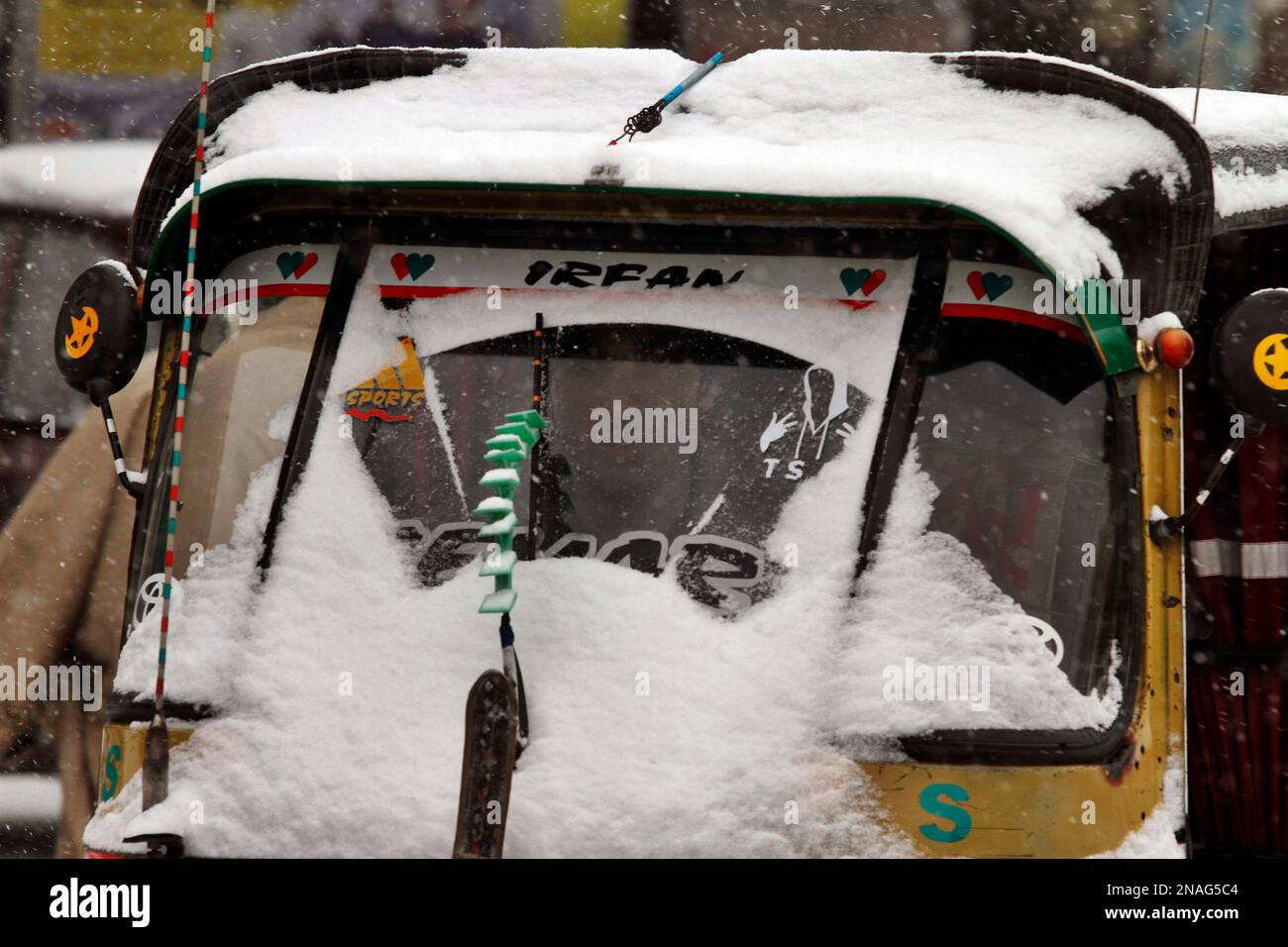 A Kashmiri auto rickshaw driver looks out from the snow-covered ...