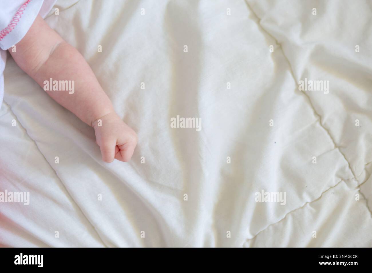 Hand baby clenched into fist on bed. child is sleeping. Hands of child ...