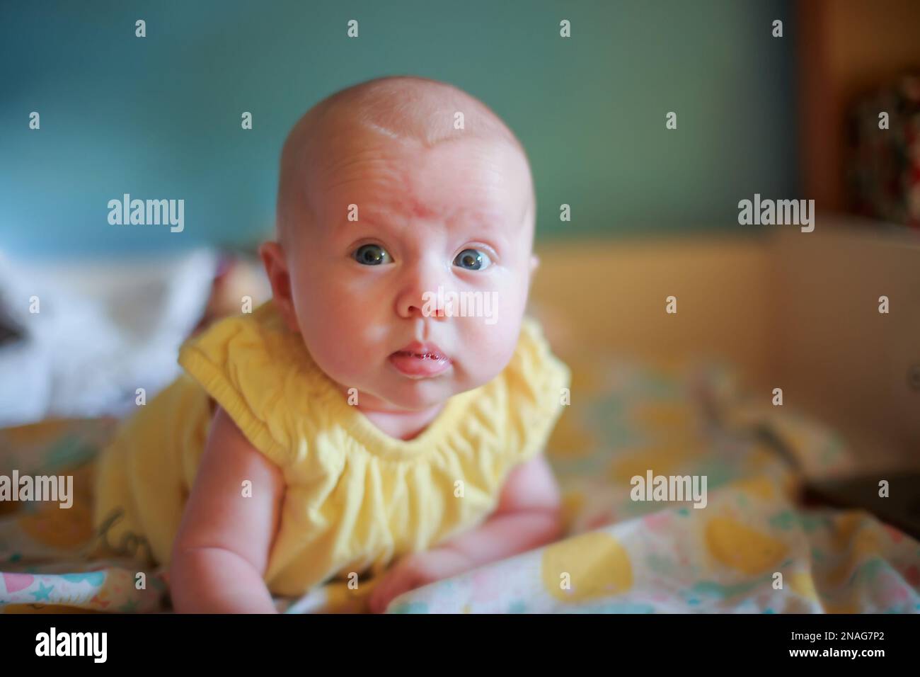 An infant in yellow clothes is lying on a changing table in the ...