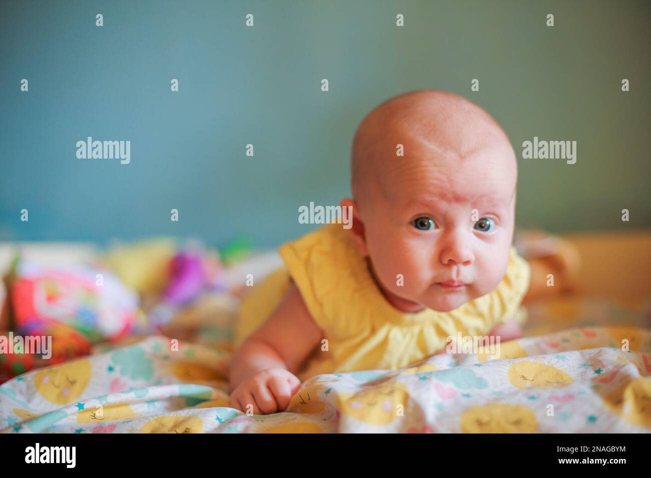 An infant in yellow clothes is lying on a changing table in the ...