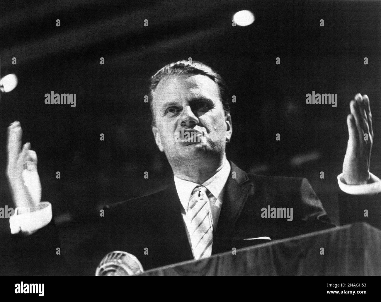 Spotlights shine on Evangelist Billy Graham as he preaches during his ...