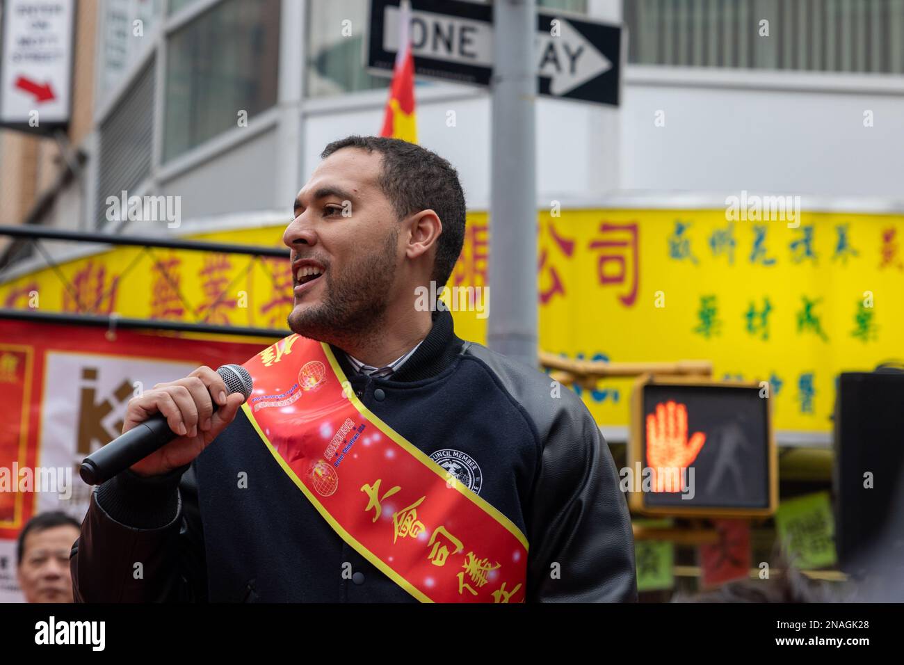 A man standing in a busy urban street, confidently holding a microphone ...
