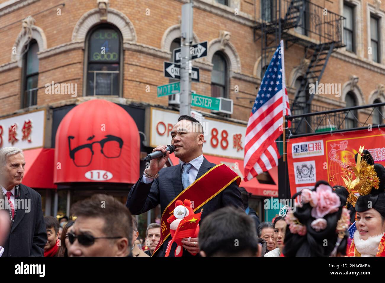 A confident male speaker addressing a large crowd of onlookers in the ...
