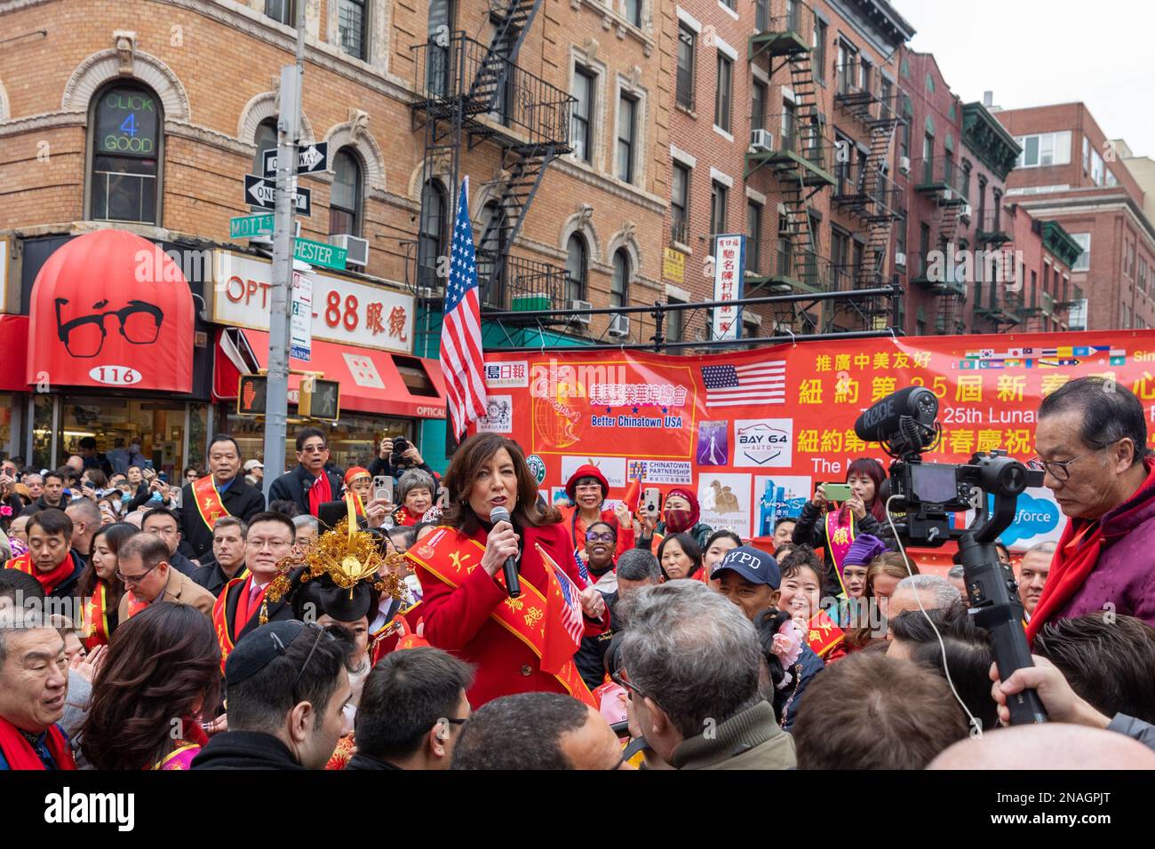 A Kathy Hochul standing in front of a vibrant backdrop of flags and ...