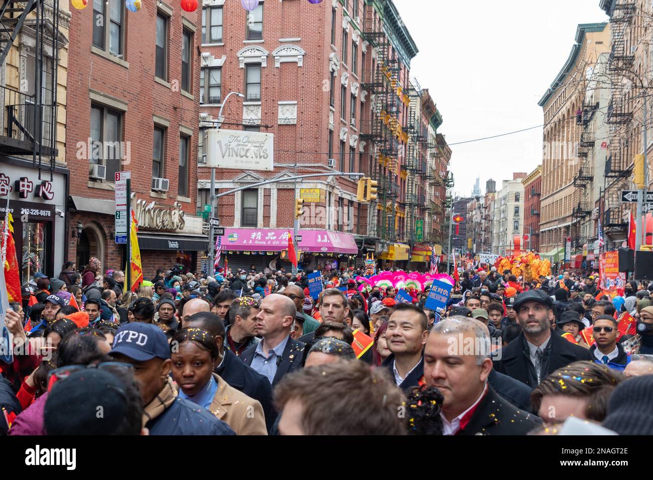 A group of people standing on a busy street corner, with a multitude of ...