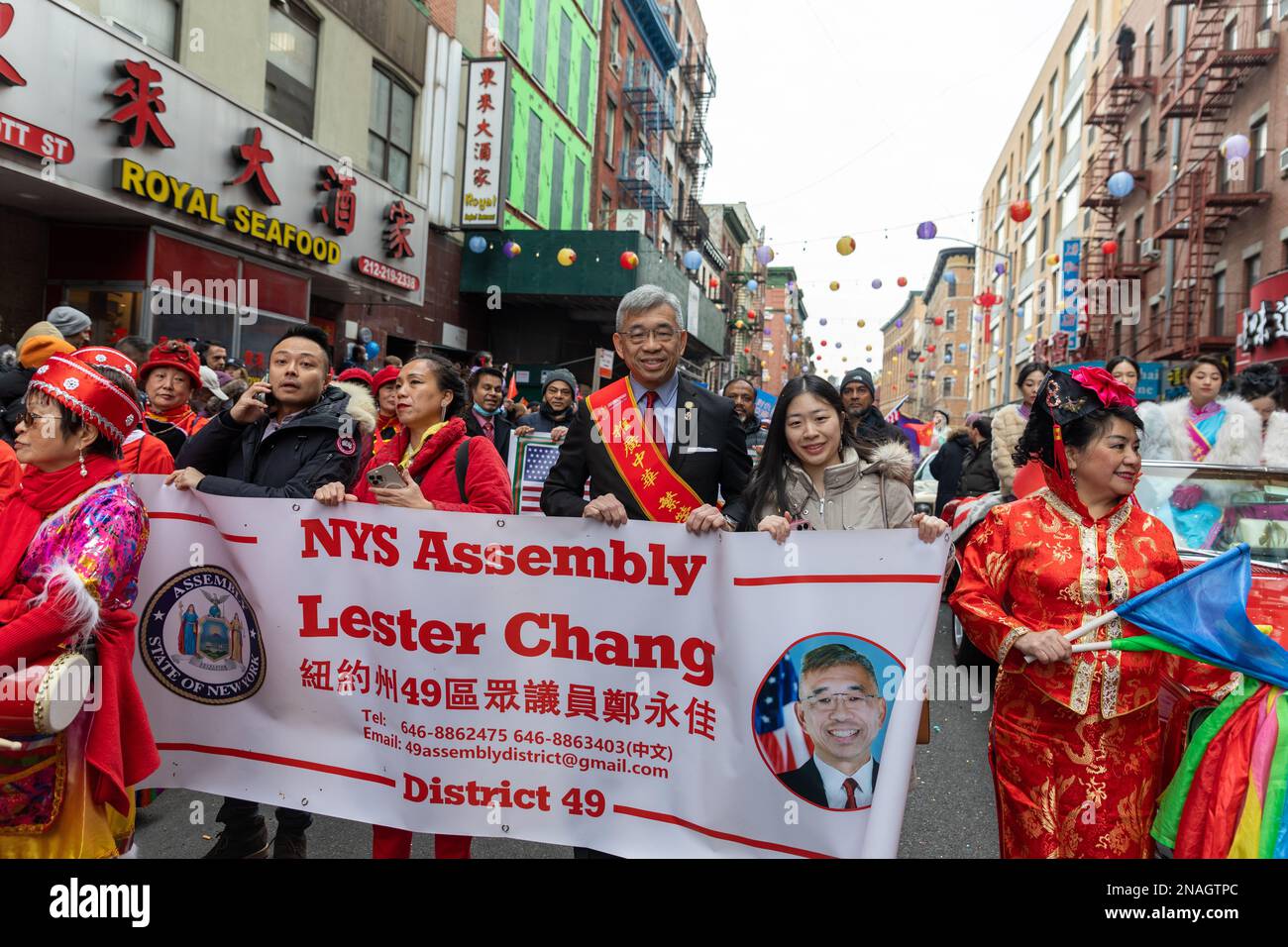 A group of happy multi-generational people carrying flags, marching in ...