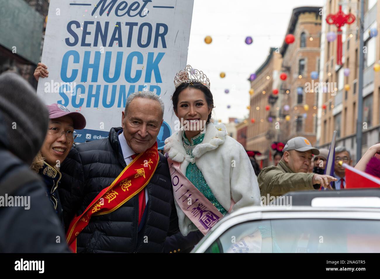 A group of people gathered together in a city street, holding a banner ...