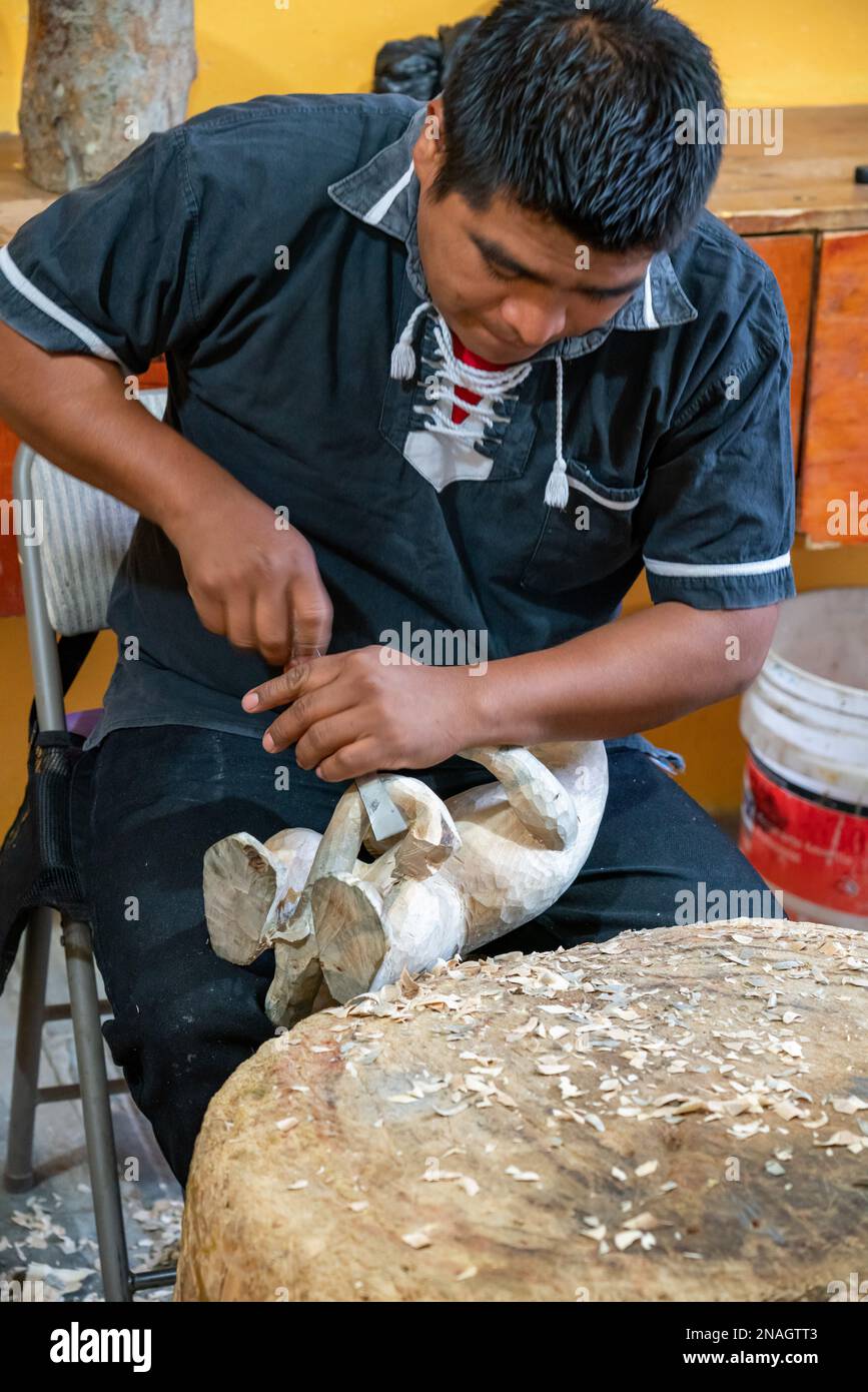 An artisan carves an alebrije spirit animal from a block of copal wood ...