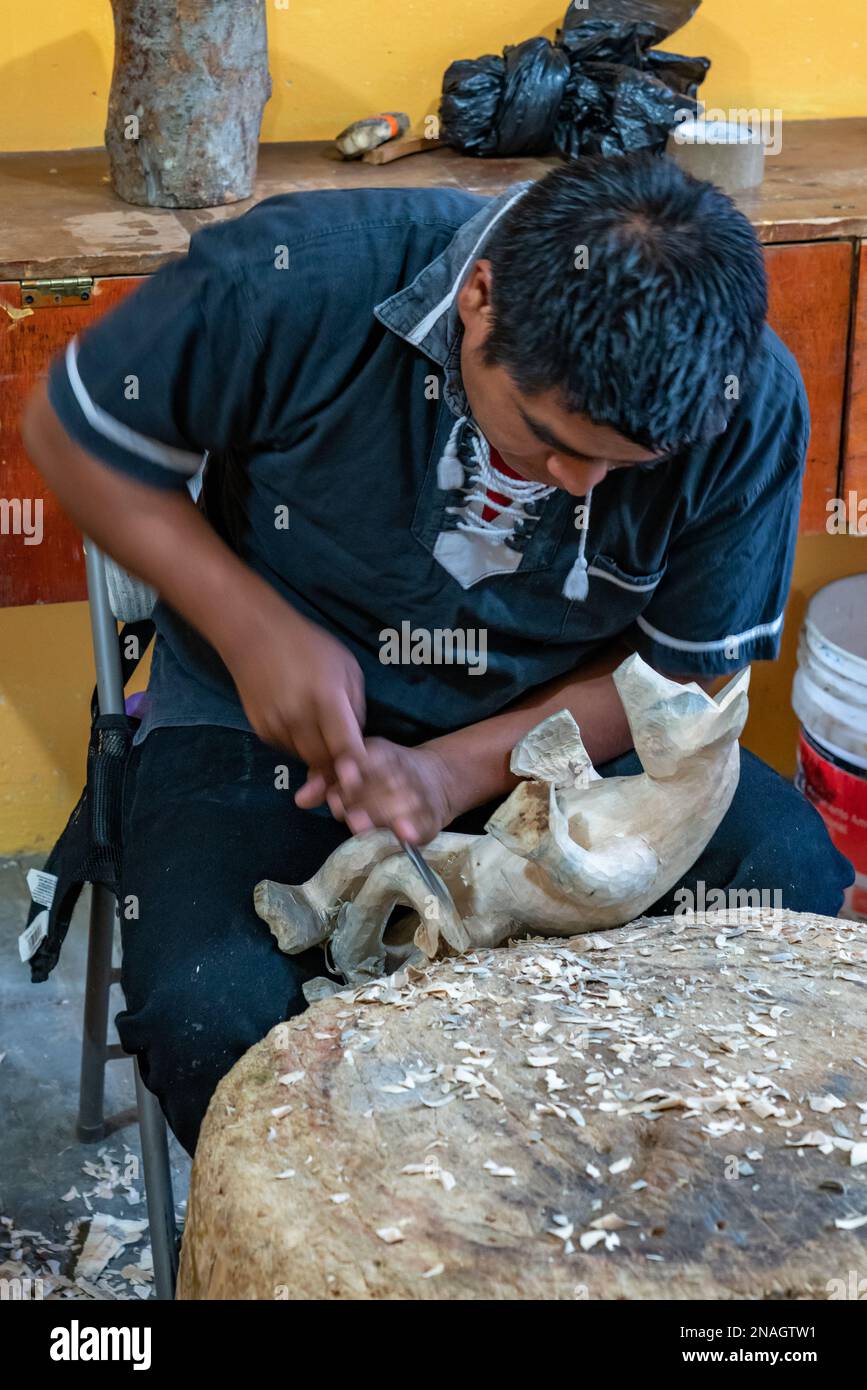 An artisan carves an alebrije spirit animal from a block of copal wood ...