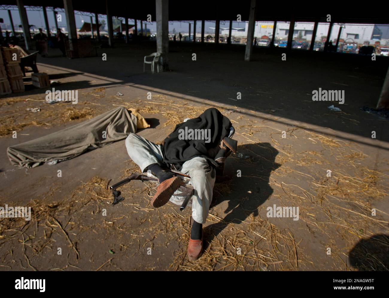 A Pakistani worker takes nap in a wheelbarrow at a wholesale fruit and ...