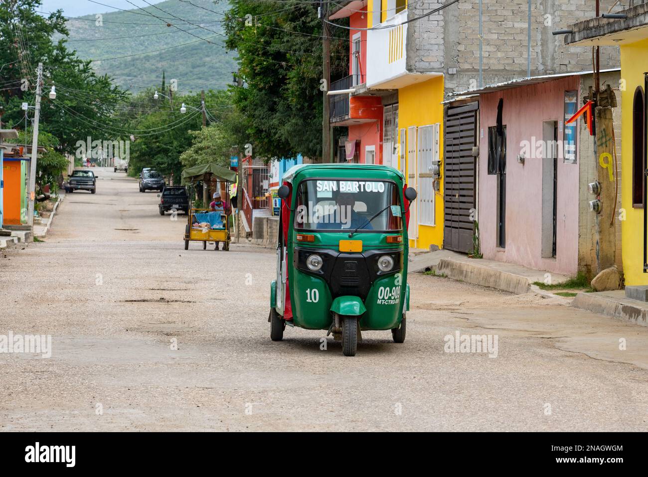 A mototaxi, tuk tuk or auto rickshaw on the street with a food cart ...