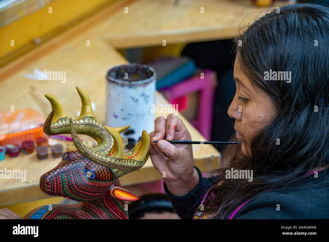 An artisan paints intricate Zapotec designs on an alebrije spirit ...