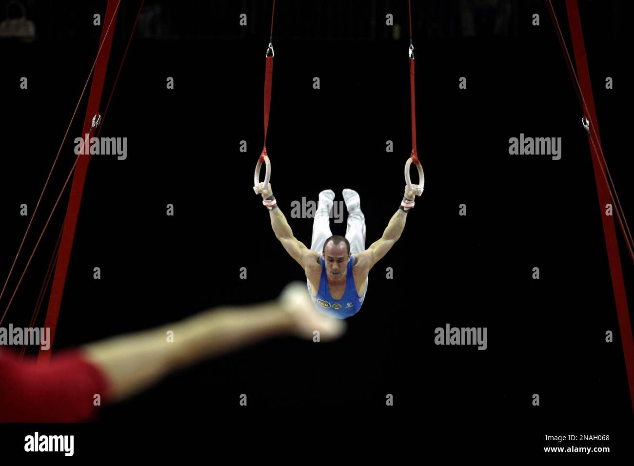 Italy's Matteo Morandi performs on the rings, as the leg is seen of ...