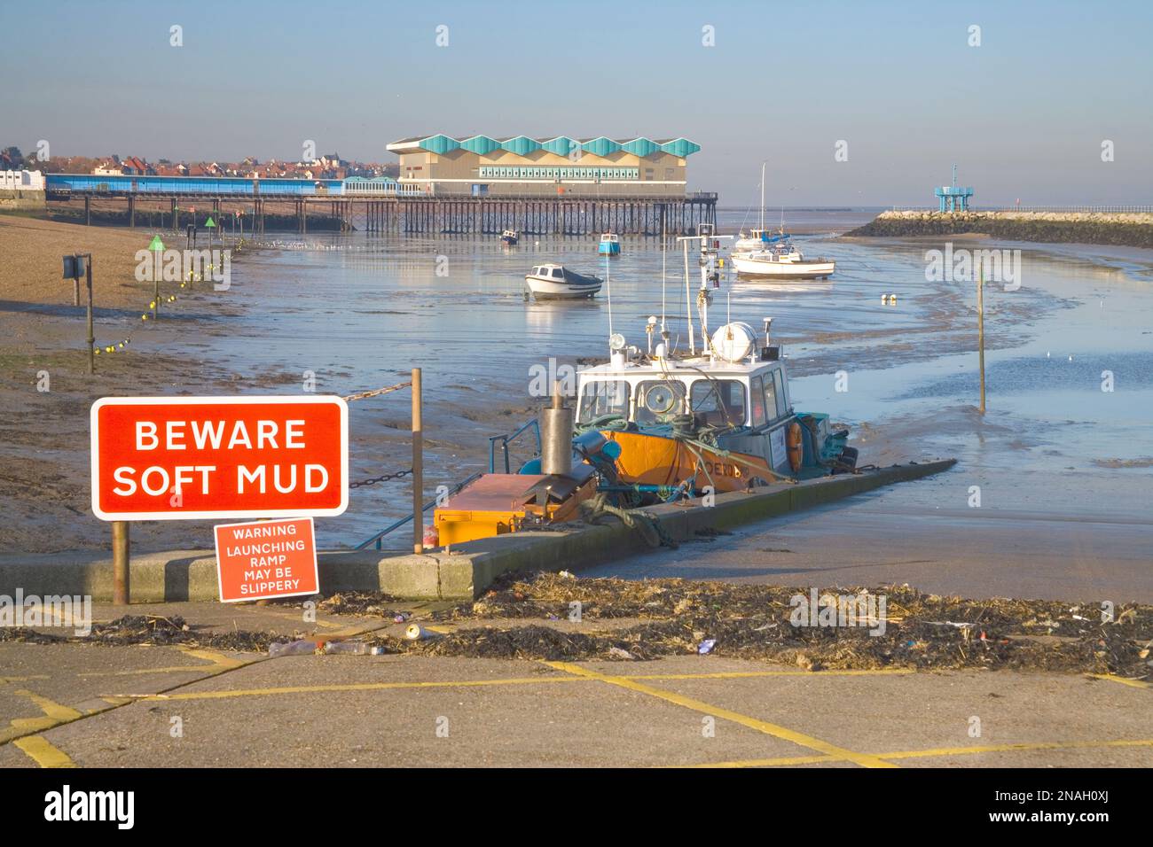 Herne Bay harbour at low tide with the pier and soft mud warning sign ...