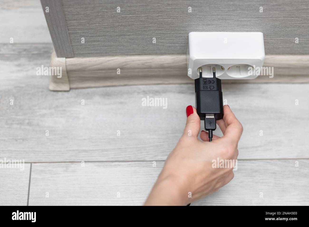 a man plugs a power supply into an outlet in a room. woman puts the ...