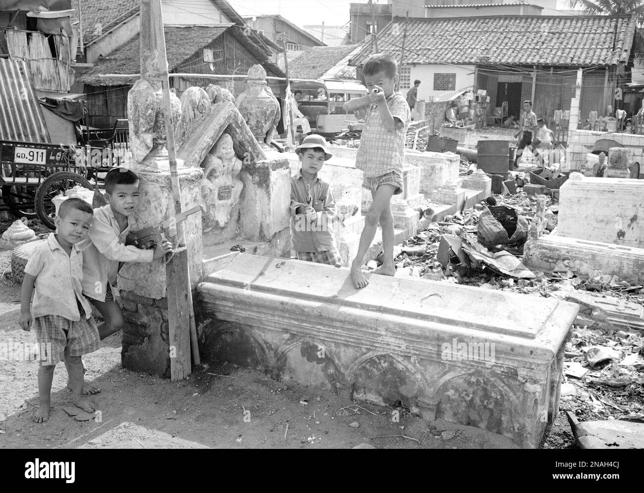Children play with plastic and wood guns at a garbage-littered ...
