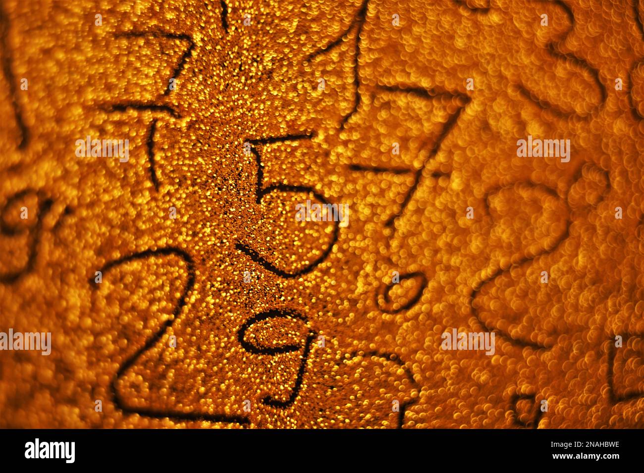 Different numbers painted on shiny sand, a numerical background on gold ...