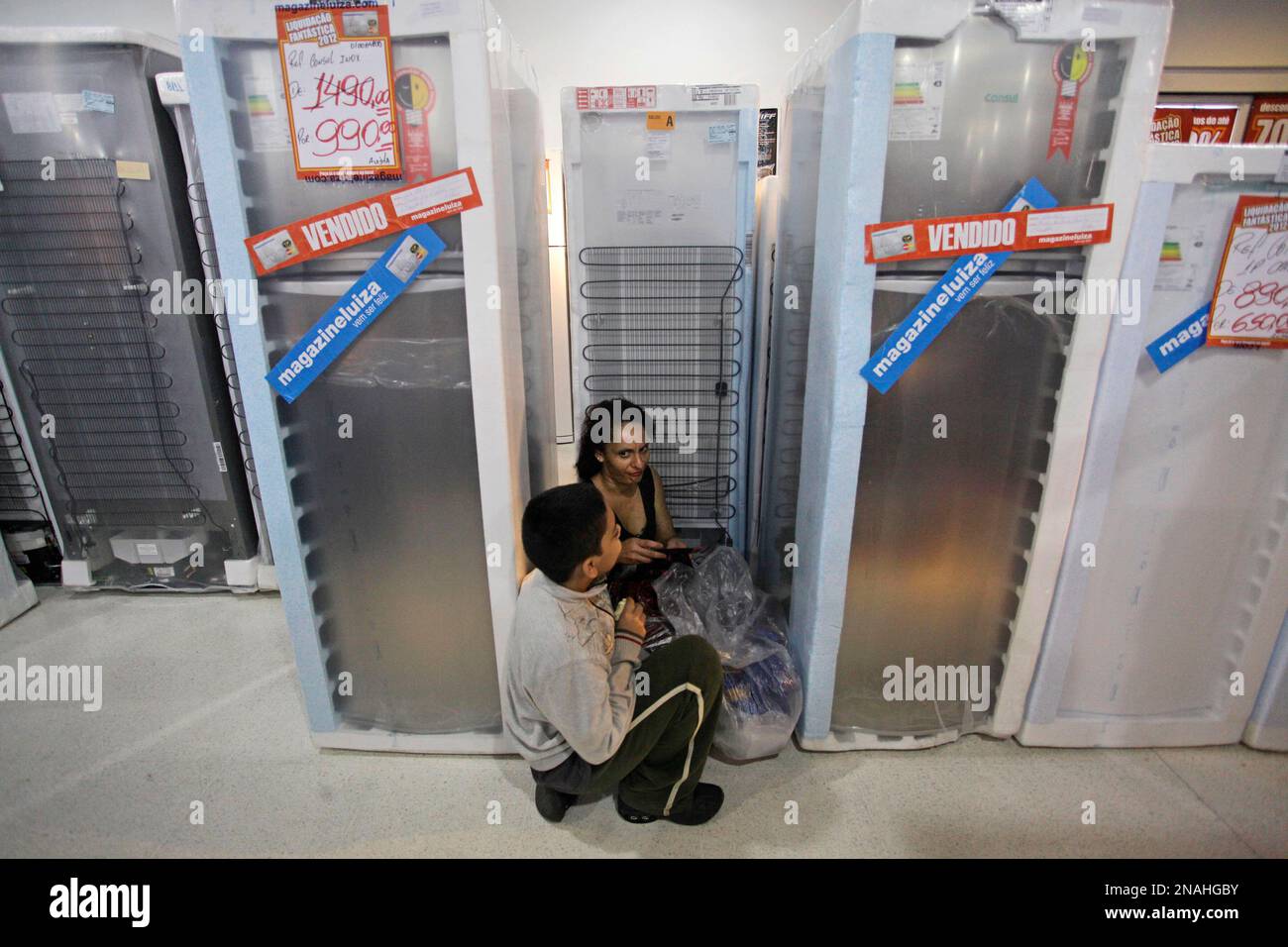 A woman sits by a refrigerator she wants to buy during a special sale ...