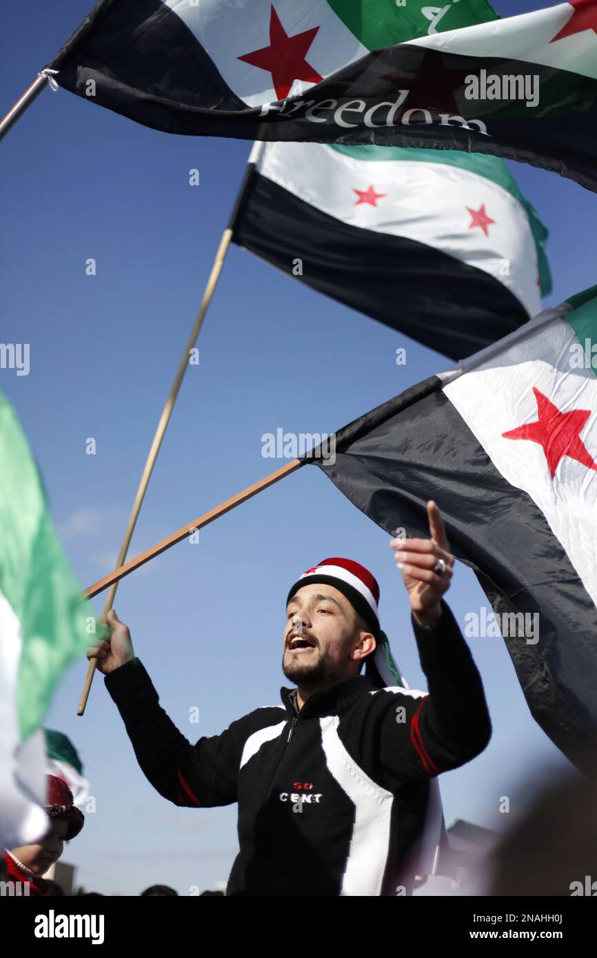 A Syrian man chants slogans and waves revolutionary flags during an ...