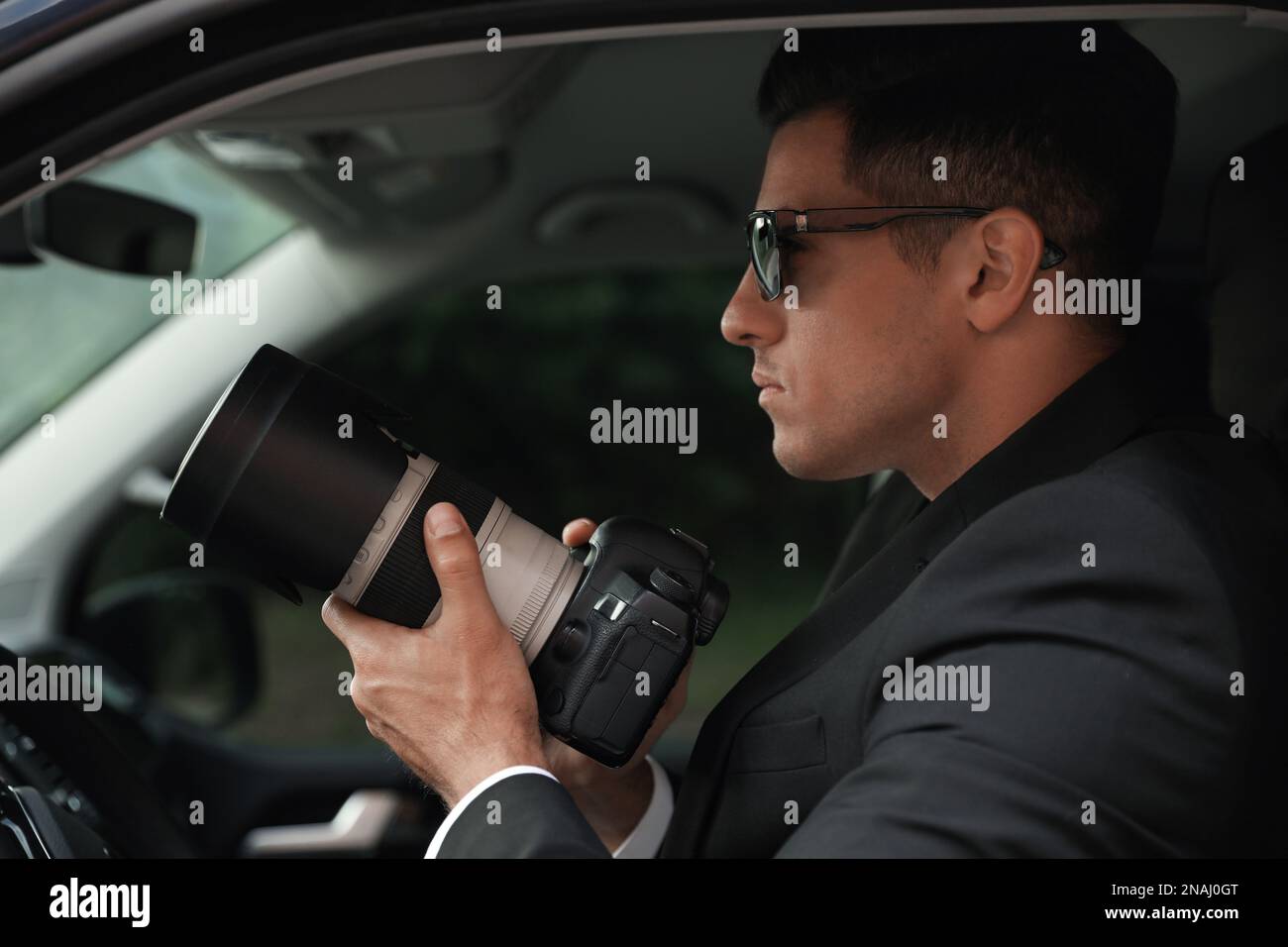 Private detective with camera spying from car Stock Photo - Alamy