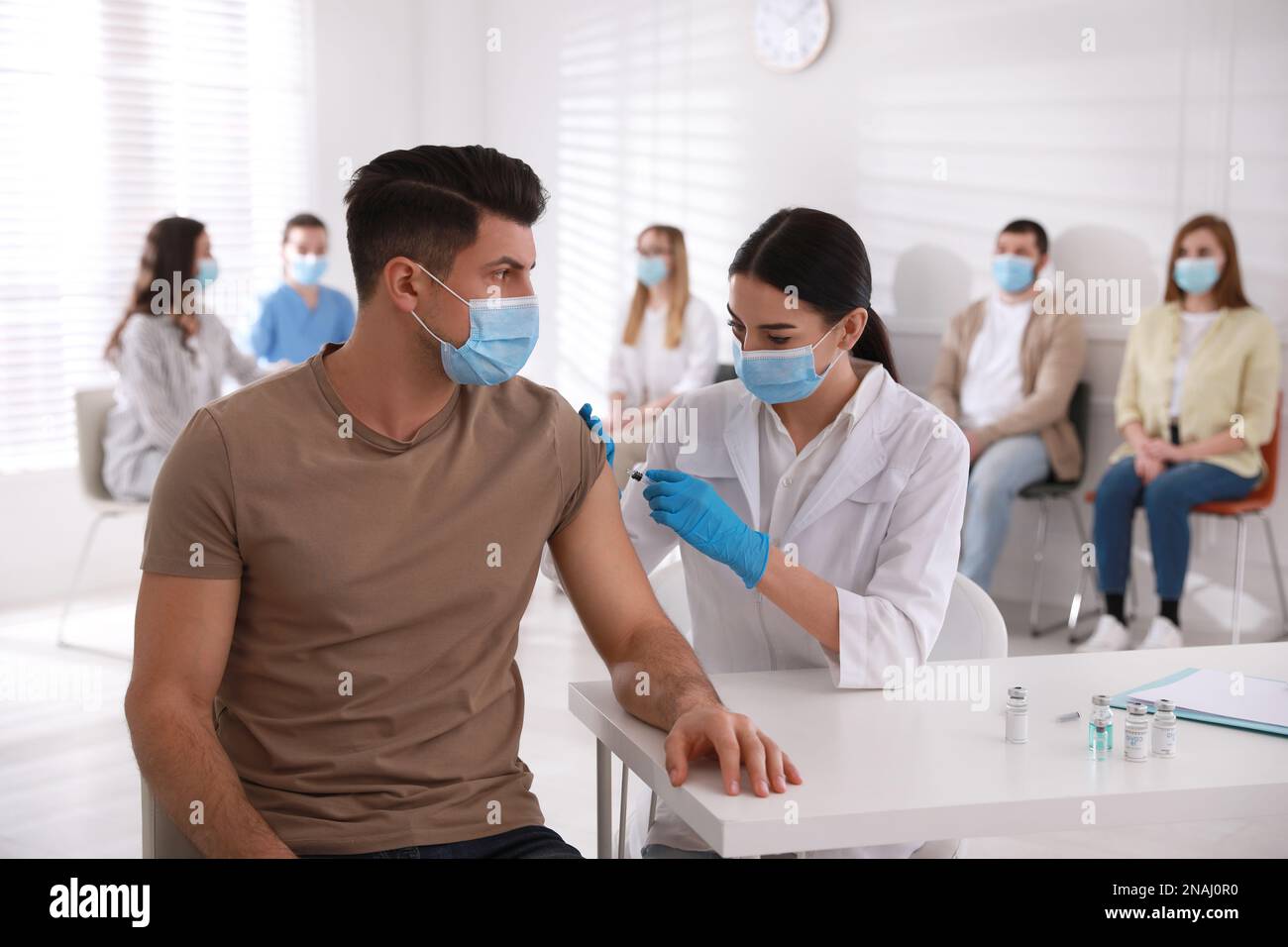 Doctor giving injection to patient while other waiting in line at ...