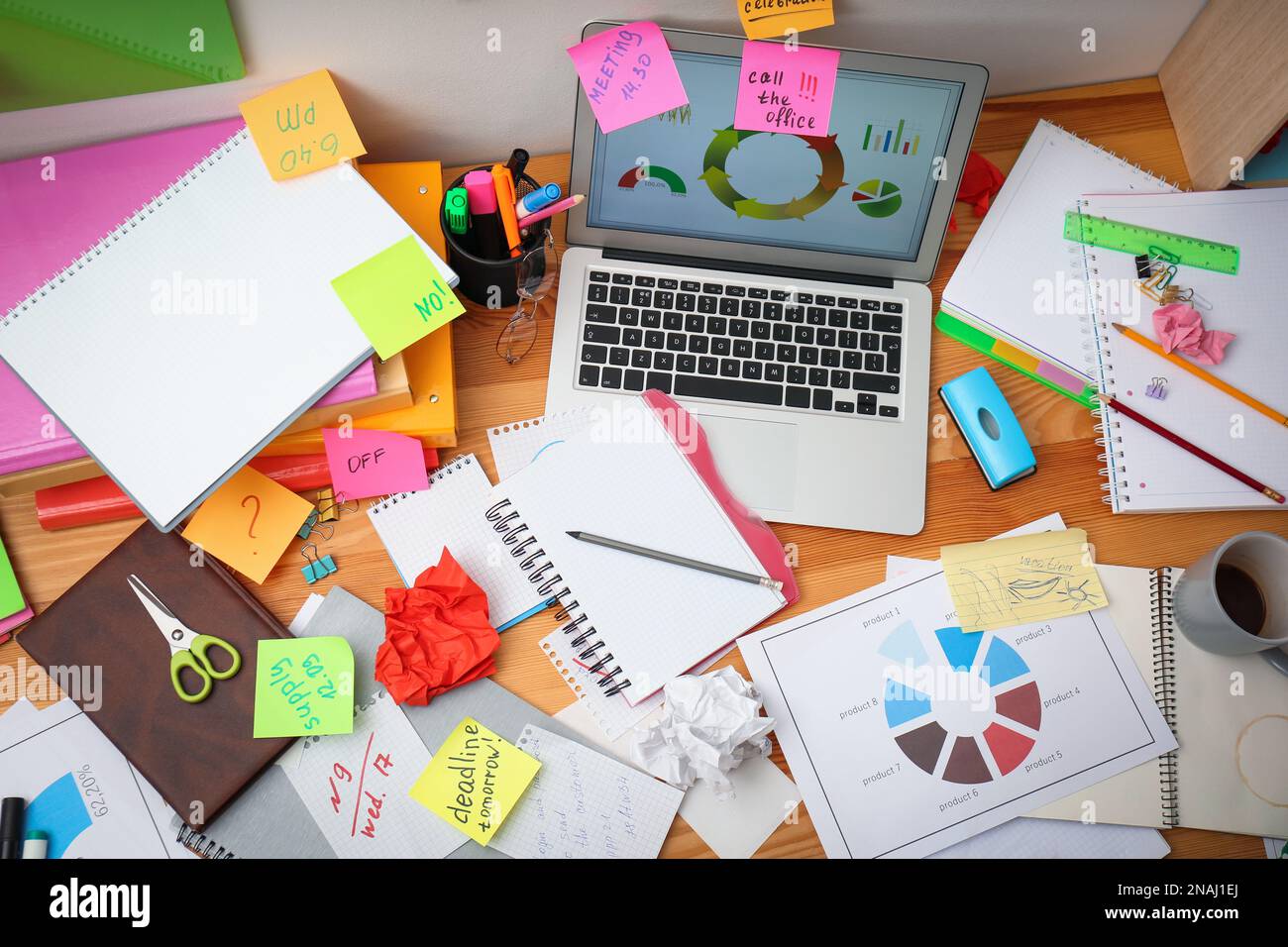 Messy table with laptop and sticky notes, above view. Concept of being ...