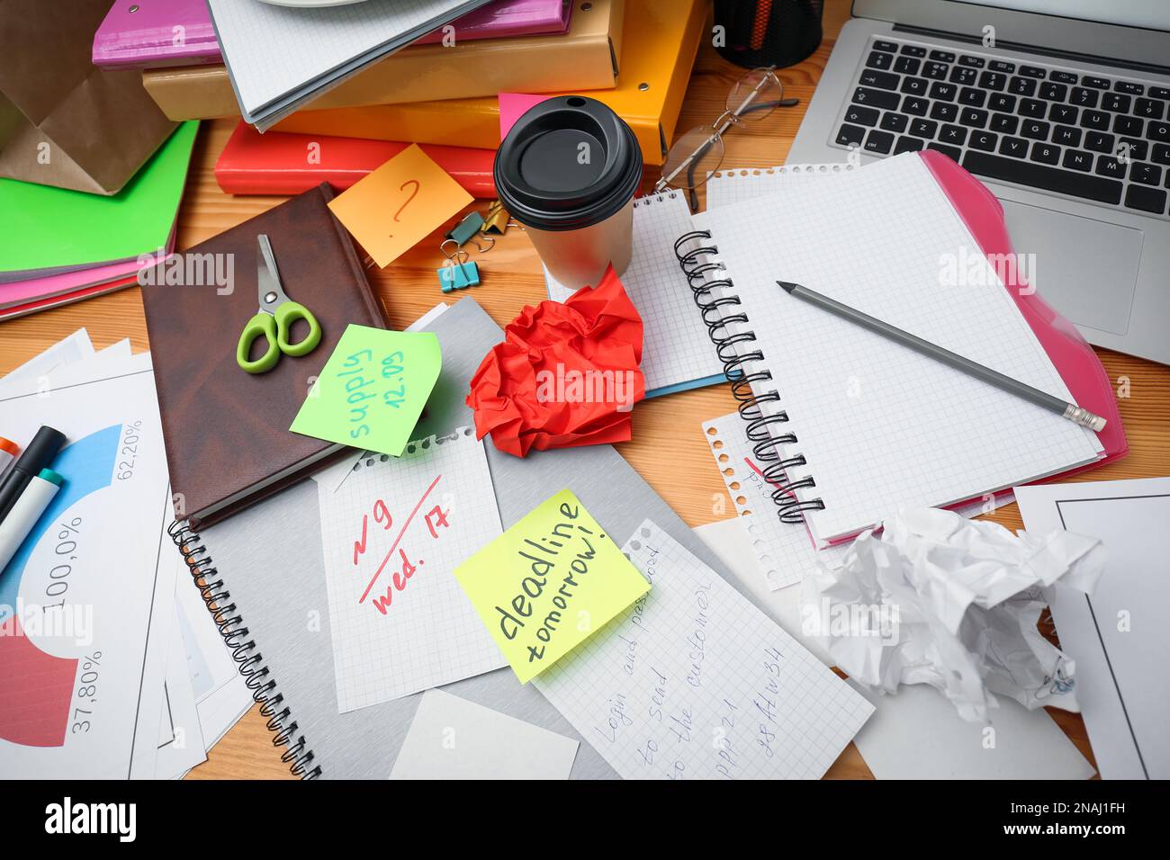 Messy table with laptop and sticky notes, above view. Concept of being ...