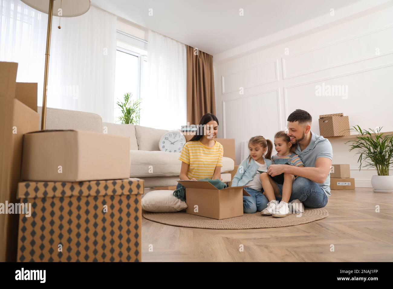 Happy family unpacking moving box at their new house Stock Photo - Alamy