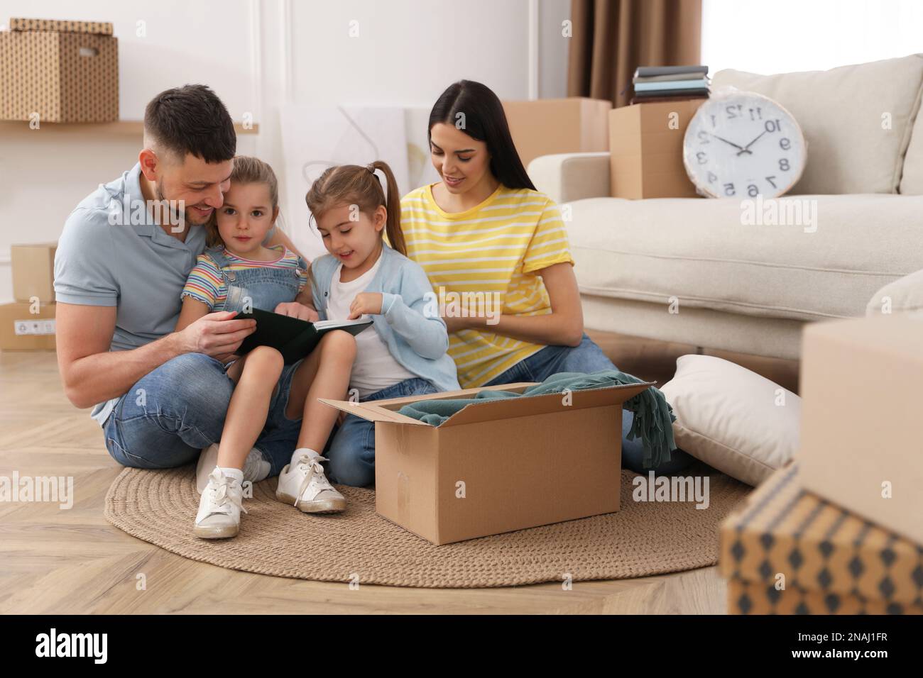 Happy family unpacking moving box at their new house Stock Photo - Alamy