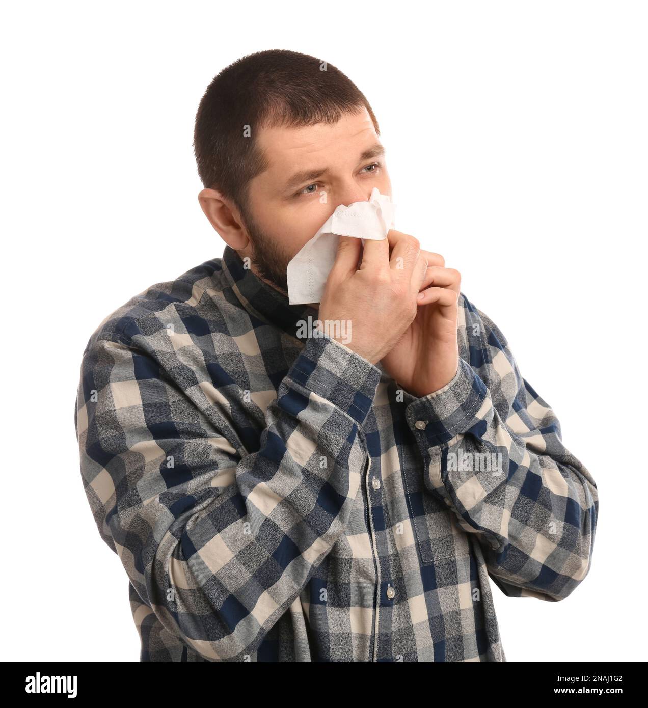 Man with tissue suffering from runny nose on white background Stock ...